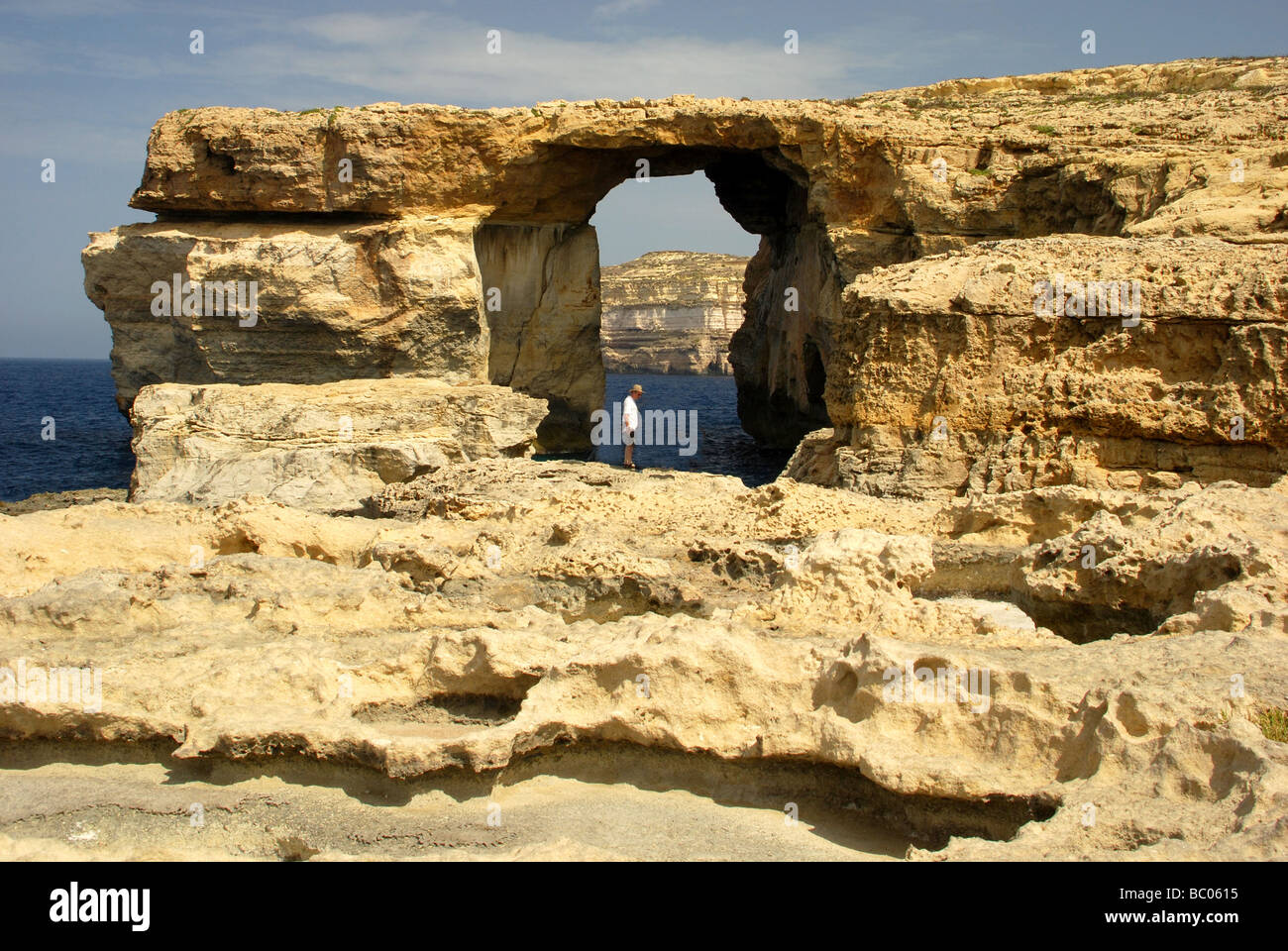 A man stands under the arch of the Azure Window on the island of Gozo ...