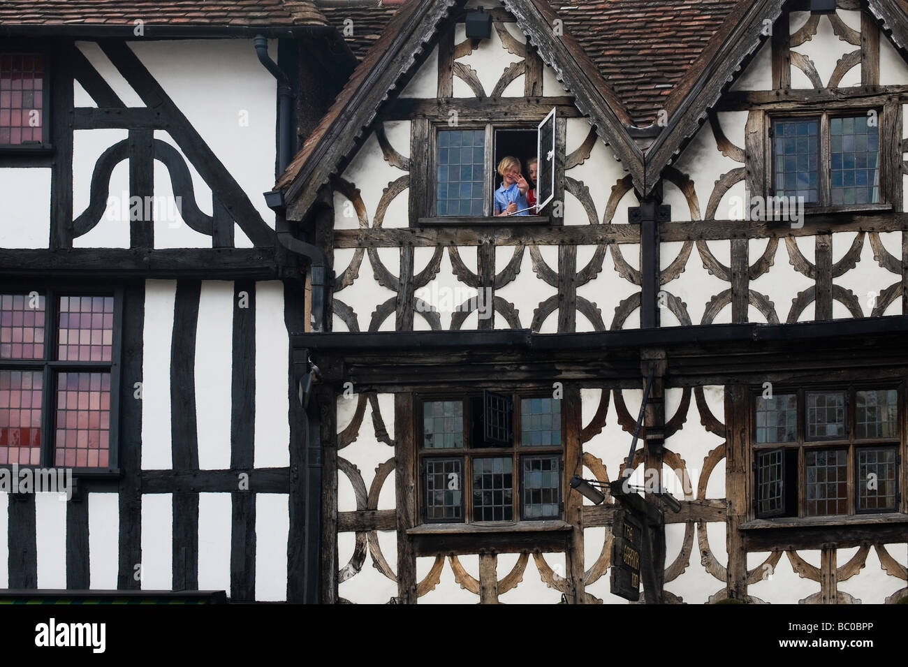 Two girls waving from a window of the Garrick inn, Stratford Upon Avon ...