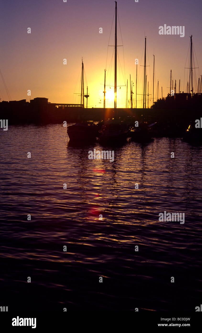 Harbour scene at sunset with silhouettes of moored sailing boats and ...