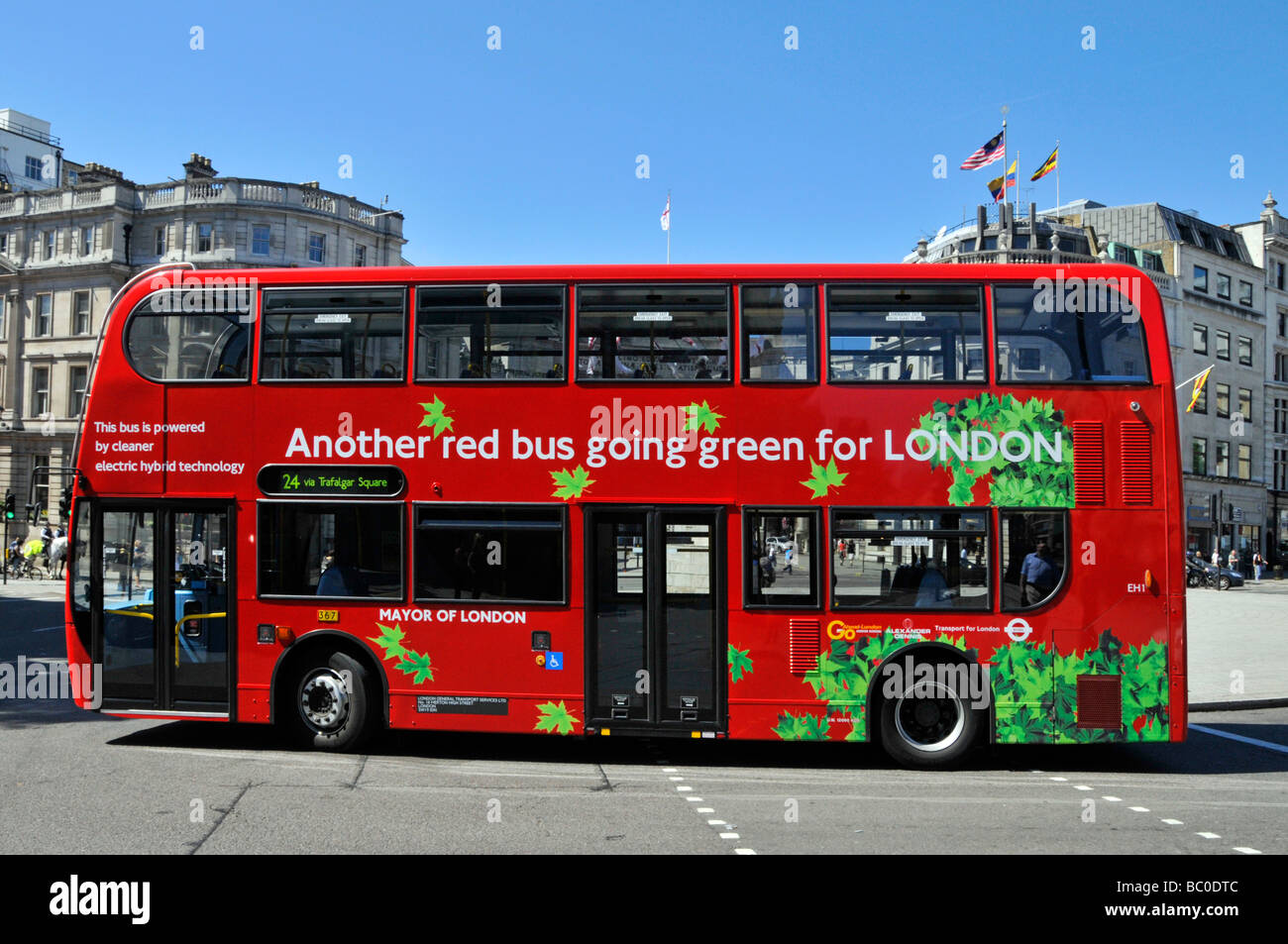 Side view of red double decker passenger bus going Green for public ...