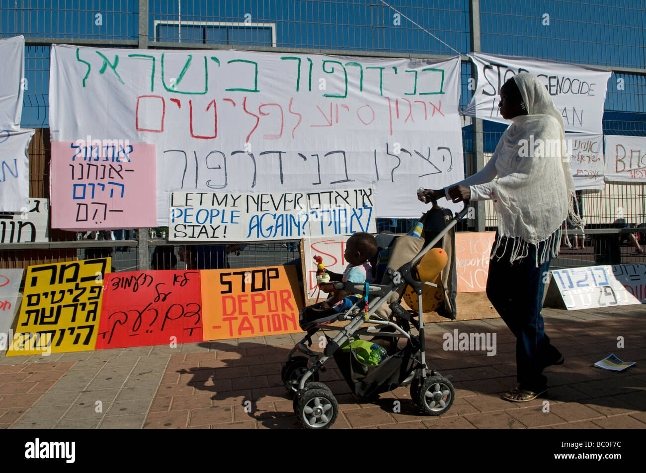 An African woman walks past placards supporting African asylum seekers ...