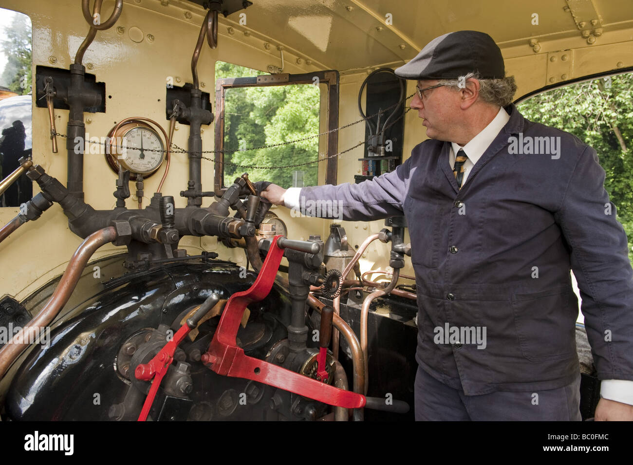Train driver/fireman in engine cab of steam locomotive engine on the ...