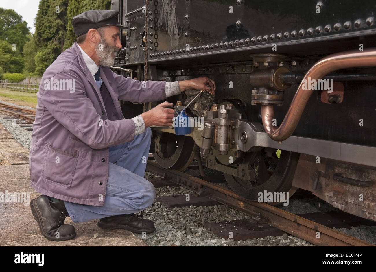 Volunteer Narrow Gauge steam engine driver carefully oils/lubricates ...