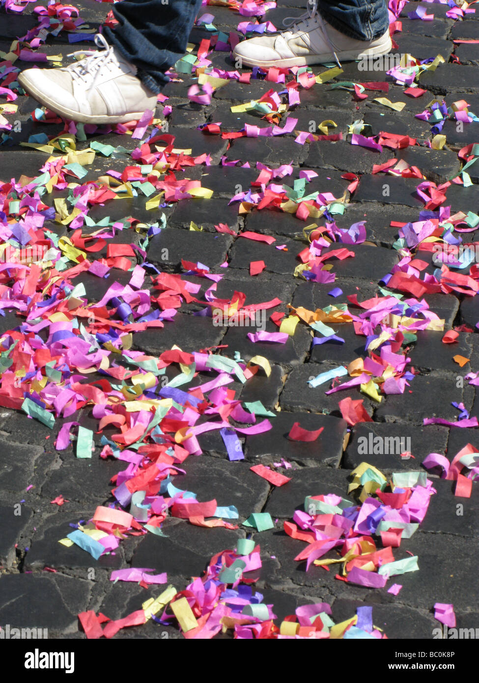 lots of colourful confetti and garlands on paved street road in sun ...