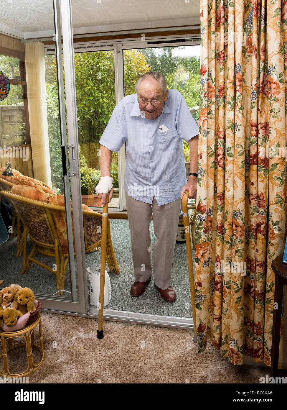 Old man uses walking sticks to help him walk through his house Stock ...