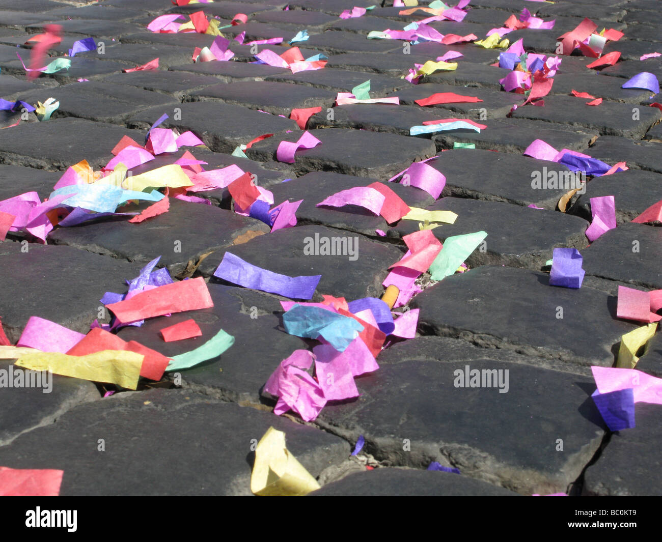 lots of colourful confetti and garlands on paved street road in sun ...