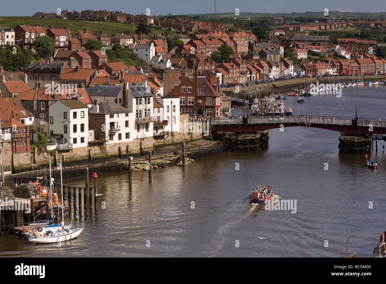 A tourist boat goes under the swing bridge in Whitby Harbour Stock ...