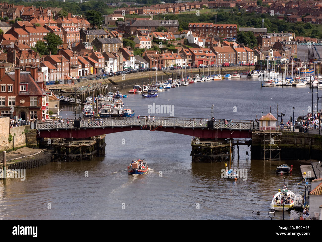 A tourist boat goes under the swing bridge in Whitby Harbour Stock ...