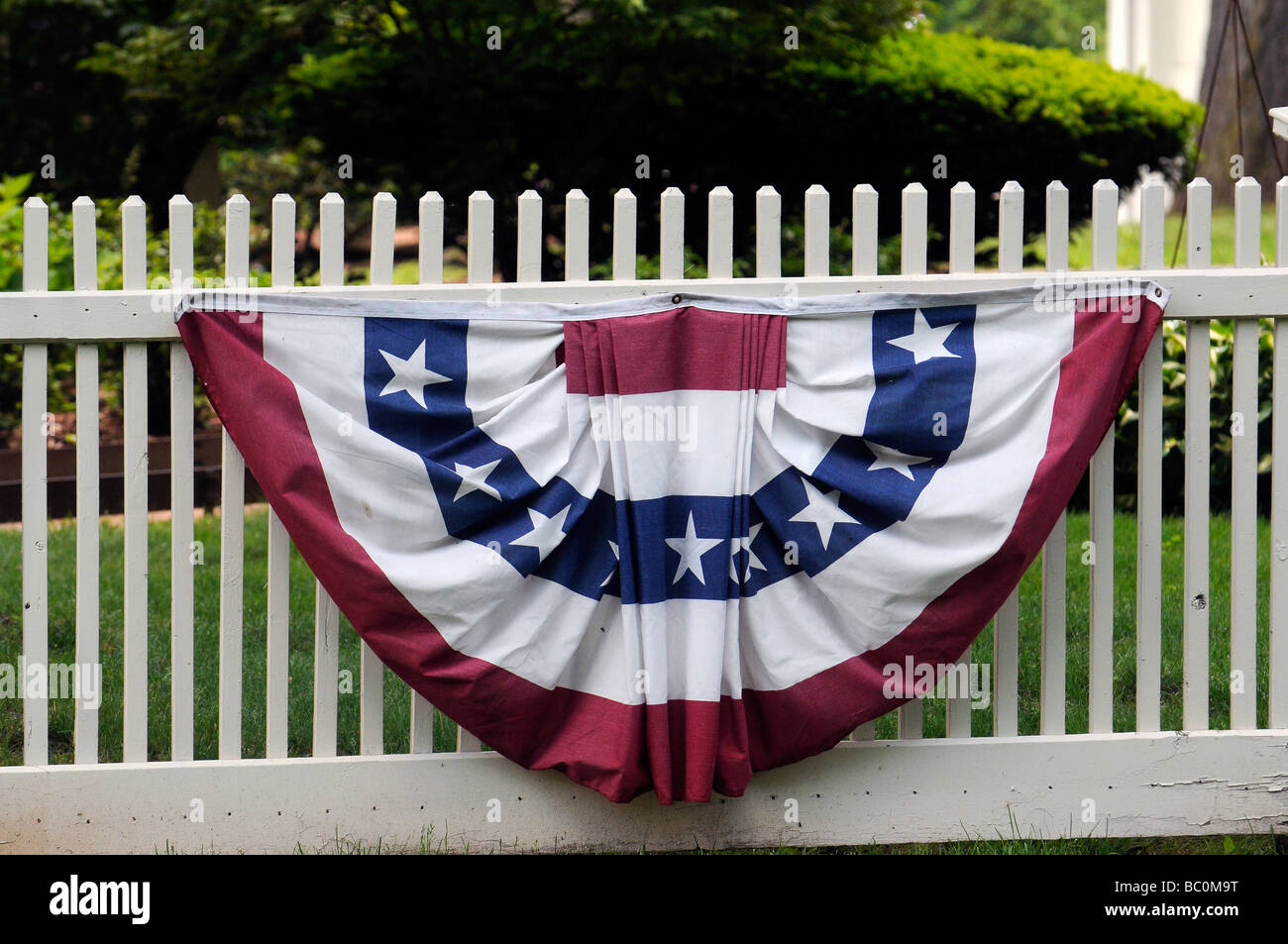 A red white and blue banner hanging from fence of colonial house in ...