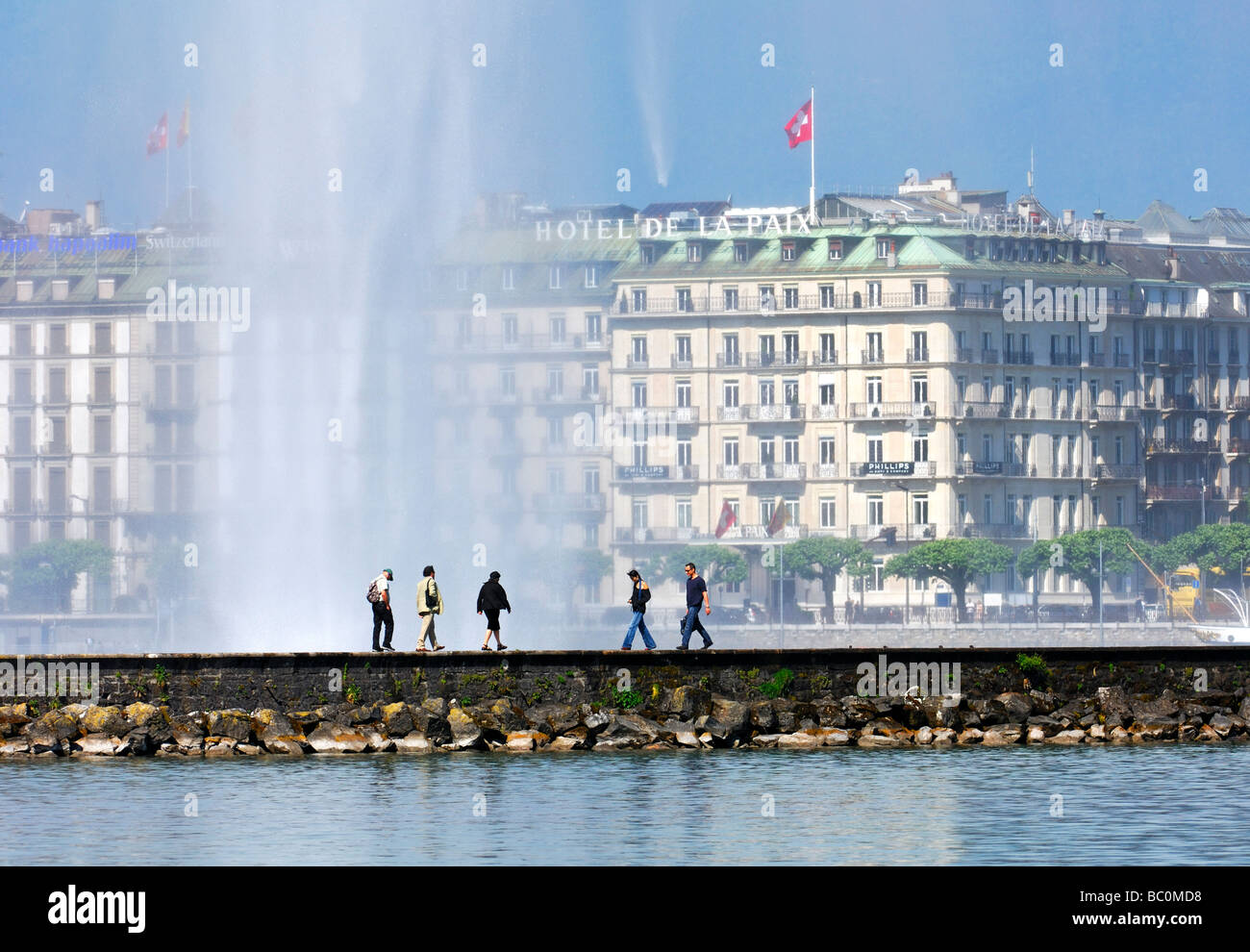 Pedestrians strolling under the pouring water of the Jet d Eau fountain ...