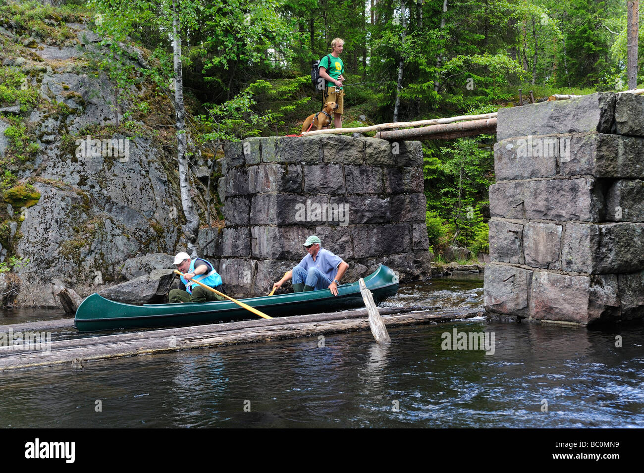 Frinds paddling canoe under a stone bridge Stock Photo - Alamy