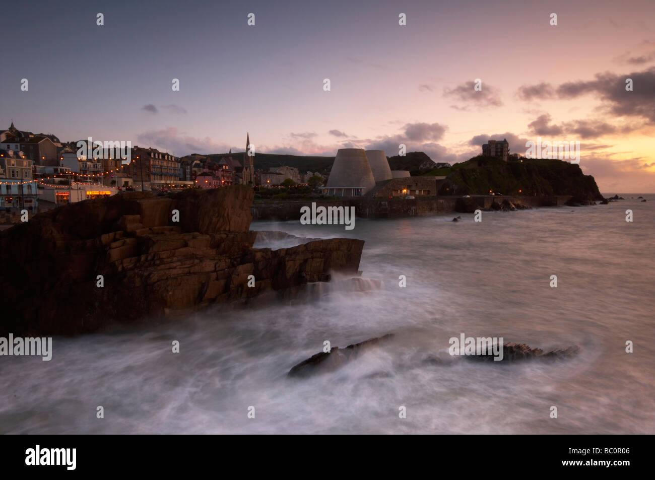 Rough seas and waves washing in over the town beach at dusk at ...