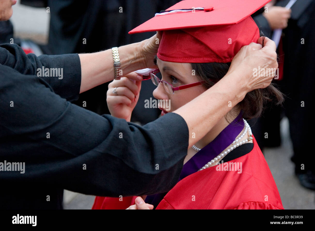 Graduation ceremony, female high school student getting cap adjusted ...
