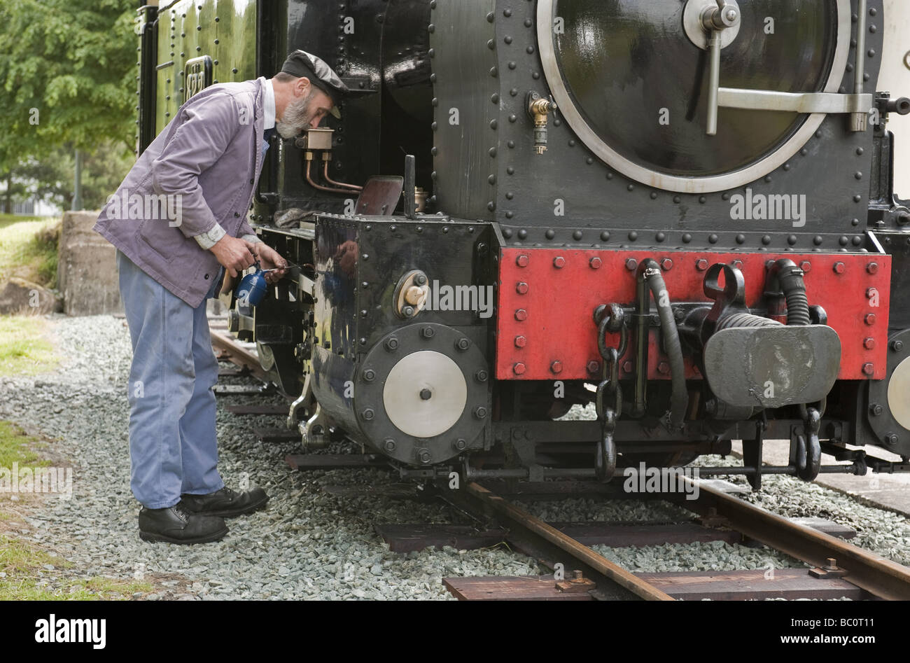 Volunteer Narrow Gauge steam engine driver carefully oils/lubricates ...