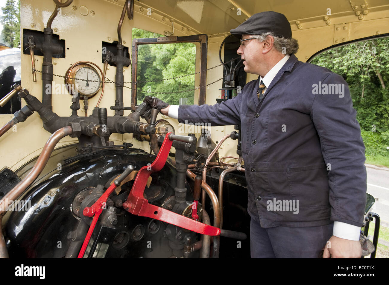 Train driver/fireman in engine cab of steam locomotive engine on the ...