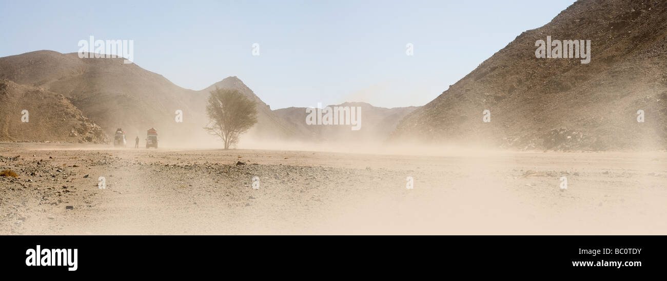 Panoramic shot of four wheel drives near lone tree in dry wadi bed in ...