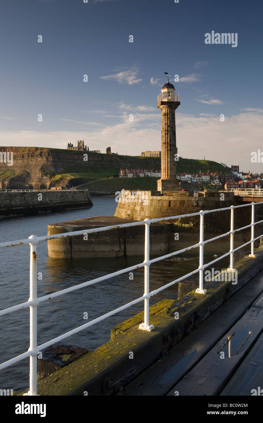 The lighthouse on Whitby Pier with St. Hilda's Abbey on the cliffs in ...