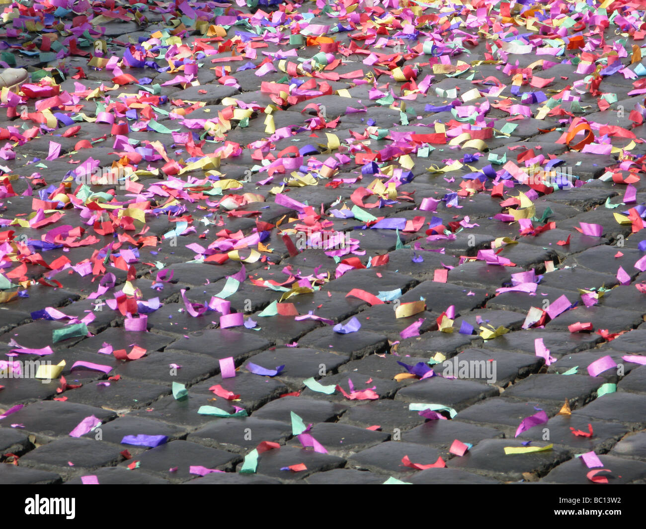 lots of colourful confetti and garlands on paved street road in sun ...