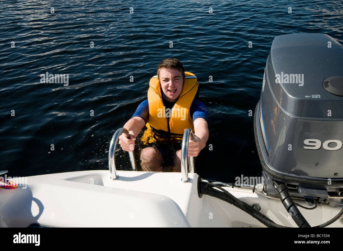 Climbing back into the boat after water skiing on Lake Brunner Stock ...