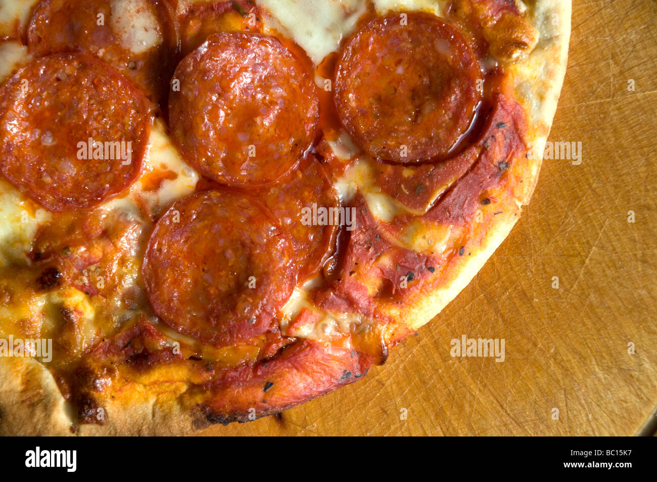 A crop of pepperoni pizza on a chopping board Stock Photo - Alamy