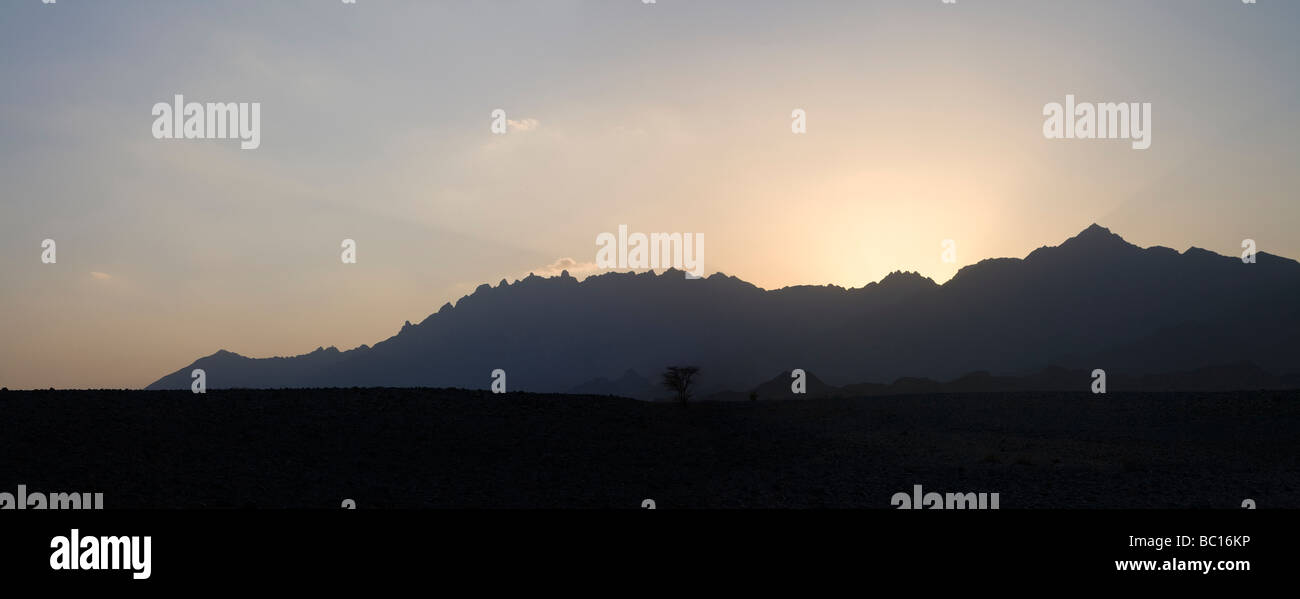 Wide panorama across desert floor to distant mountain ranges at sunset ...
