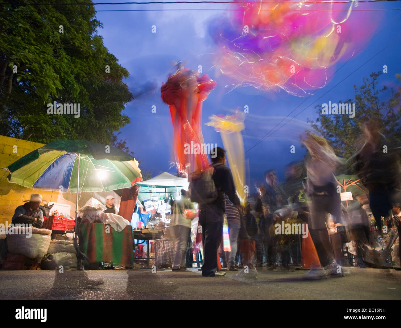 During a street festival, a man sells balloons at twilight Stock Photo ...