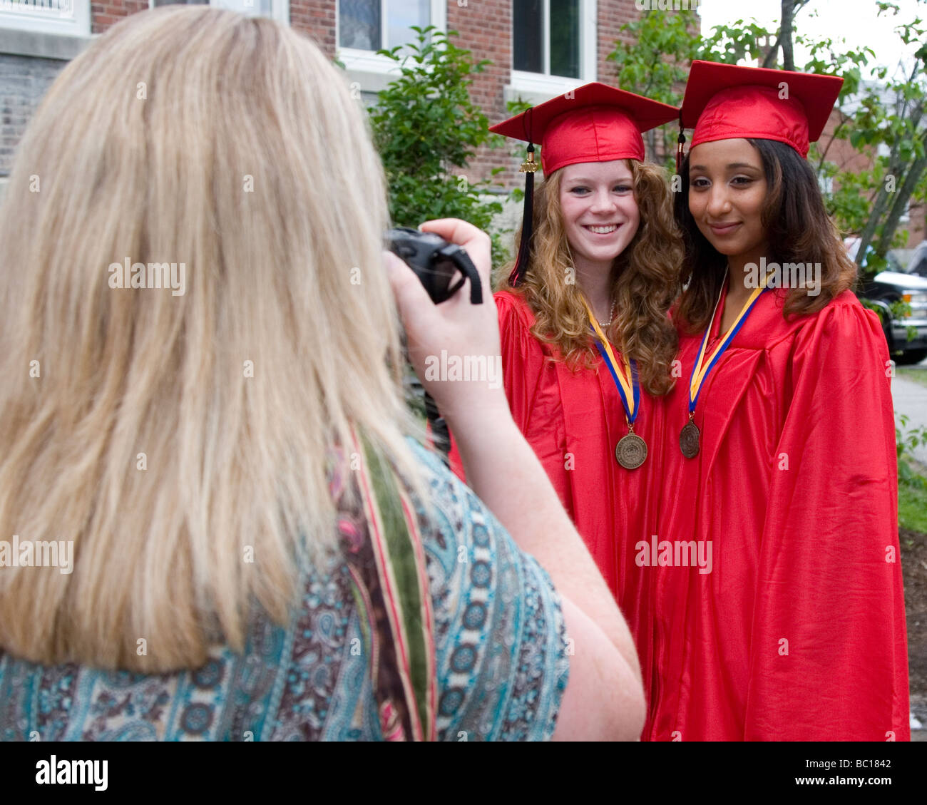 Graduation ceremony, female high school students in cap and gown pose ...