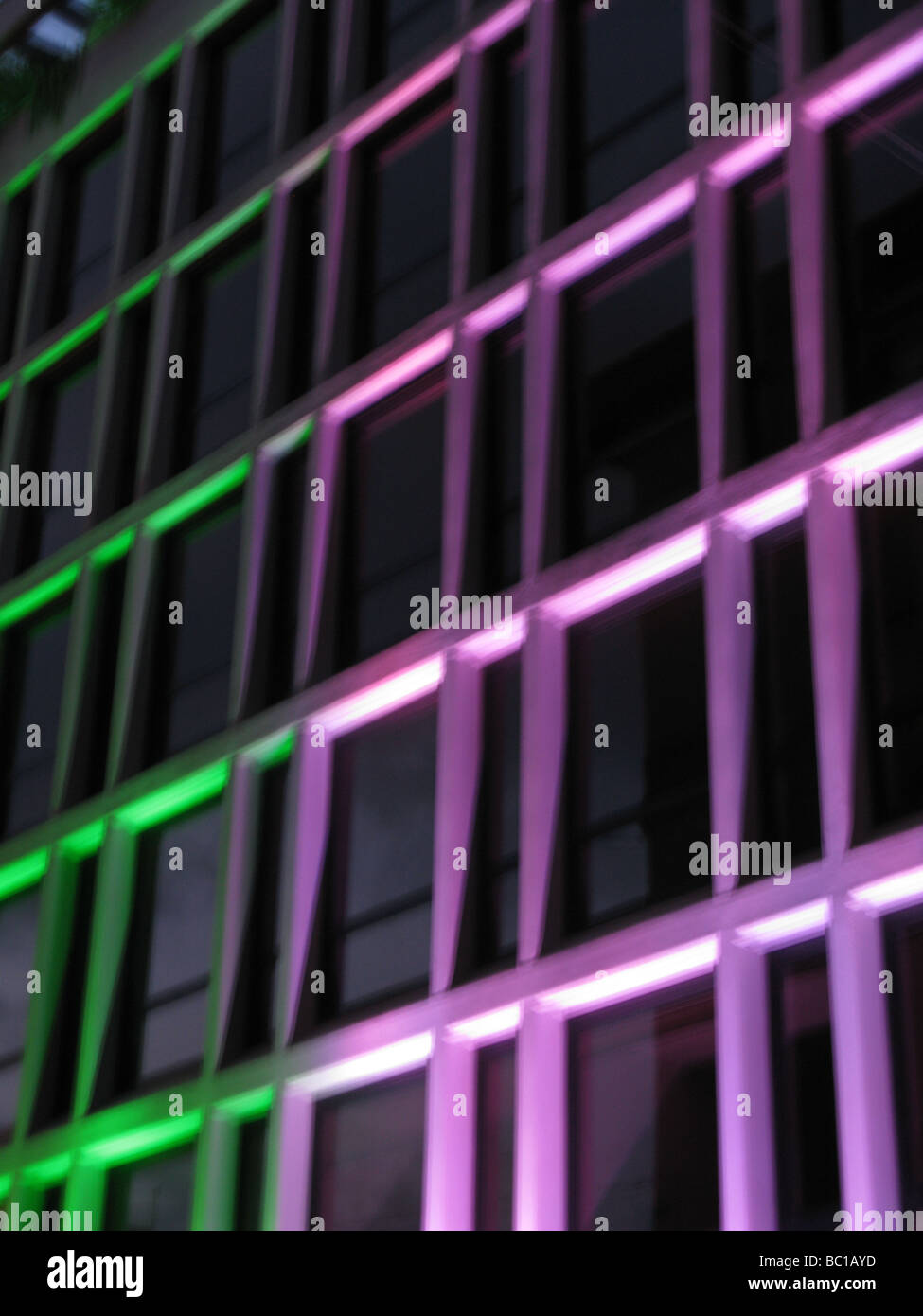 modern office block front illuminated with colourful lights at night ...