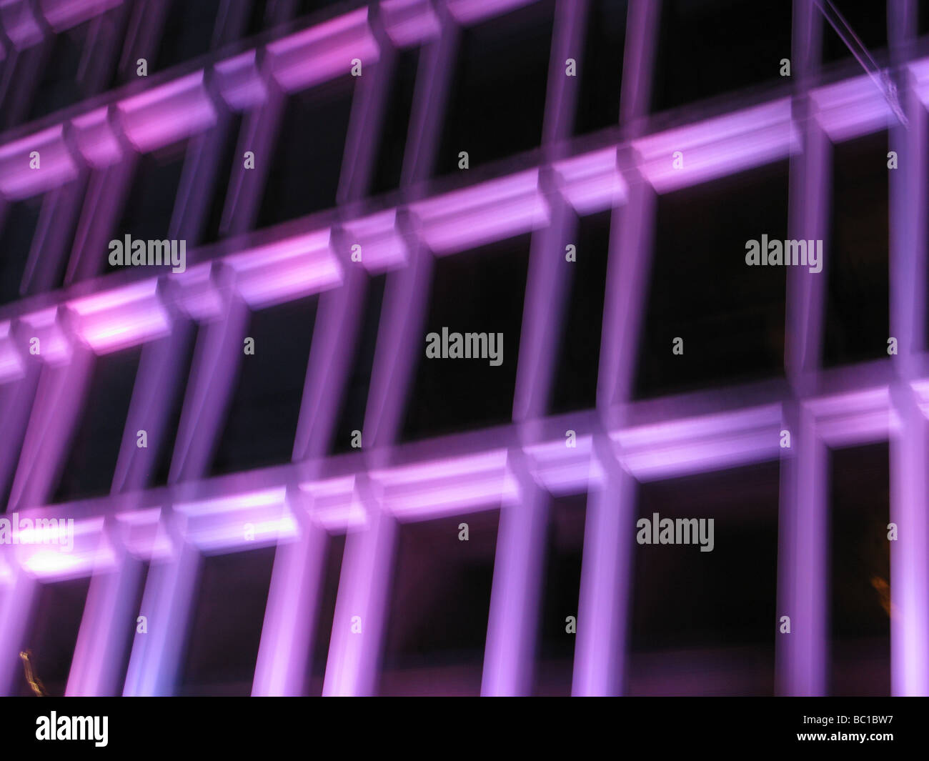 modern office block front illuminated with colourful lights at night ...