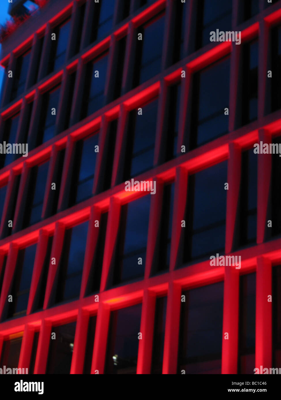 modern office block front illuminated with colourful lights at night ...