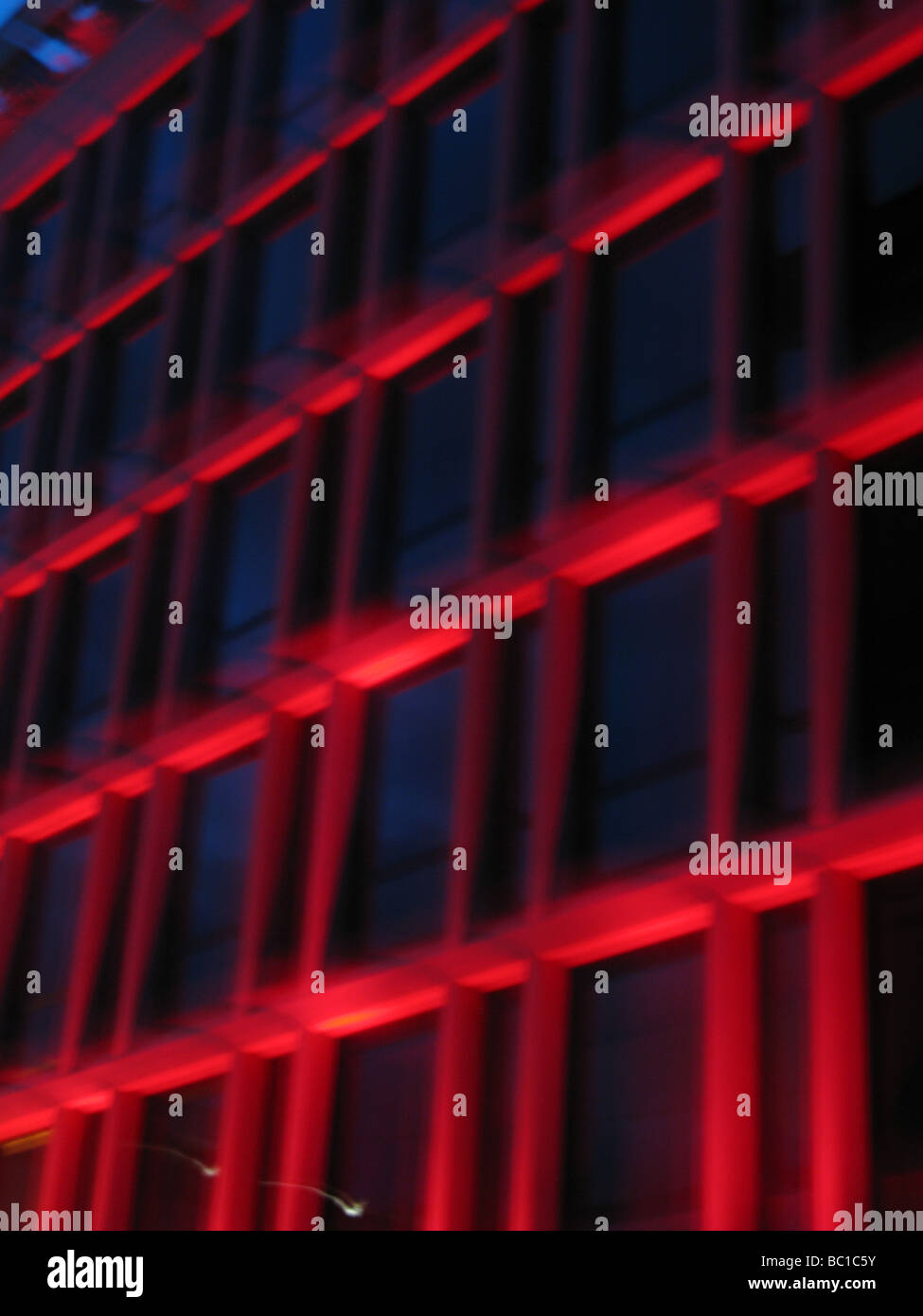 modern office block front illuminated with colourful lights at night ...