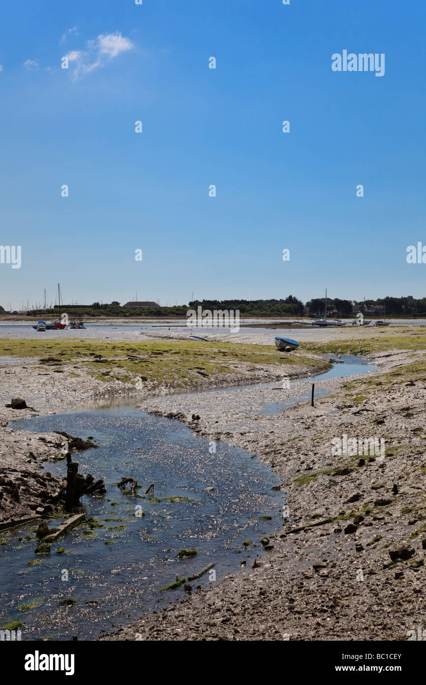 Backlit fresh water river flows into Chichester Harbour at low tide ...