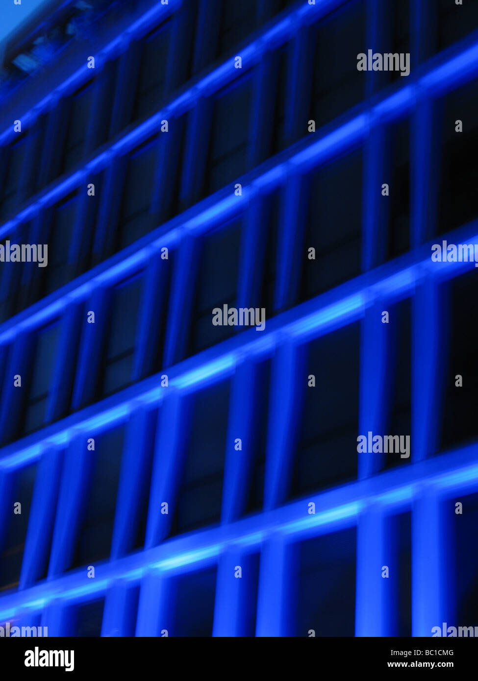 modern office block front illuminated with colourful lights at night ...