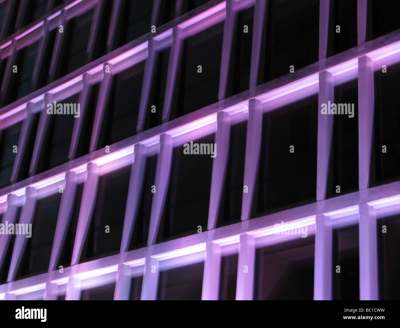 modern office block front illuminated with colourful lights at night ...