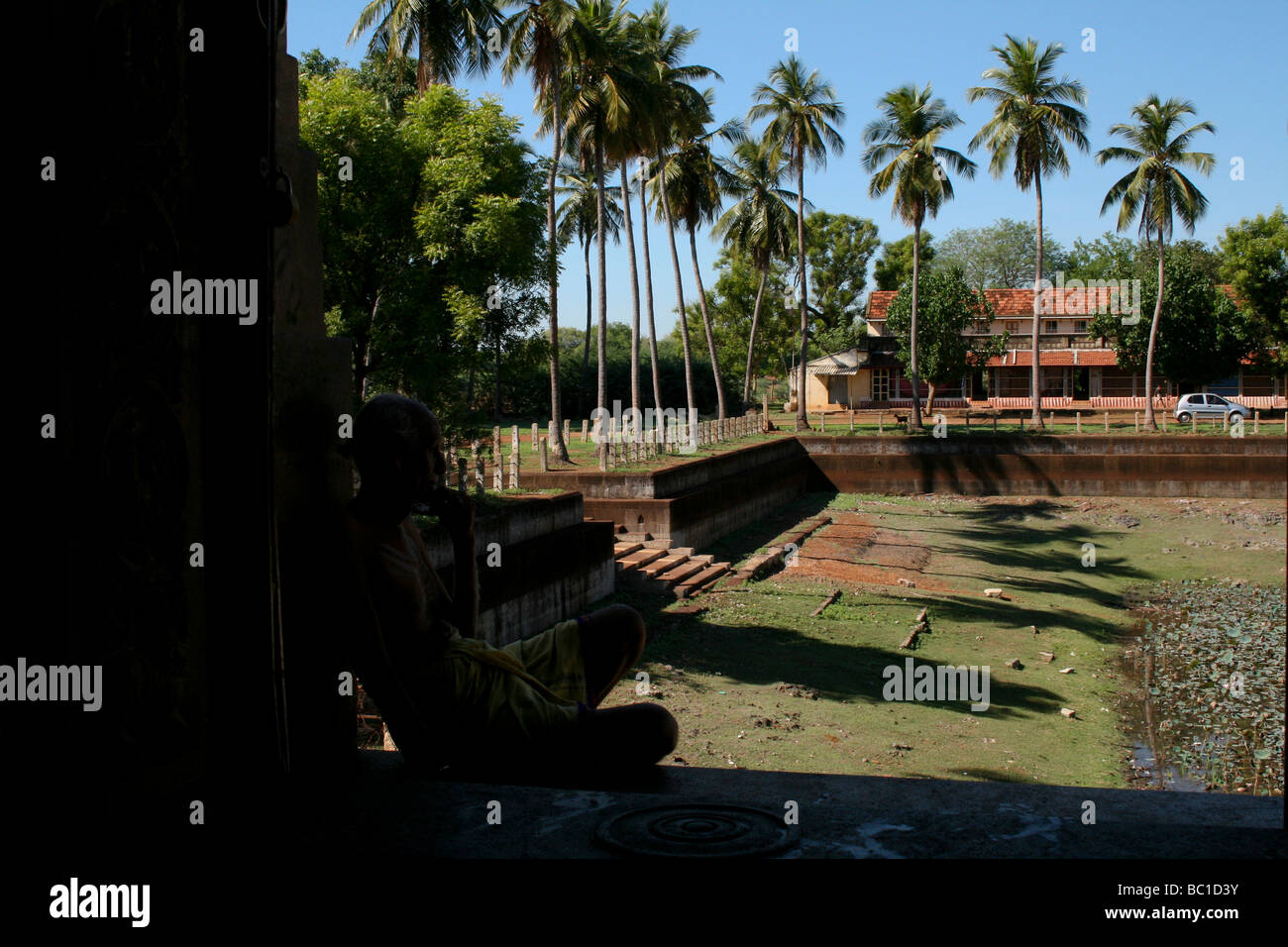 LONELY PRIEST AT THE ENTRANCE OF THE KOTTAIYUR TEMPLE IN CHETTINADU ...