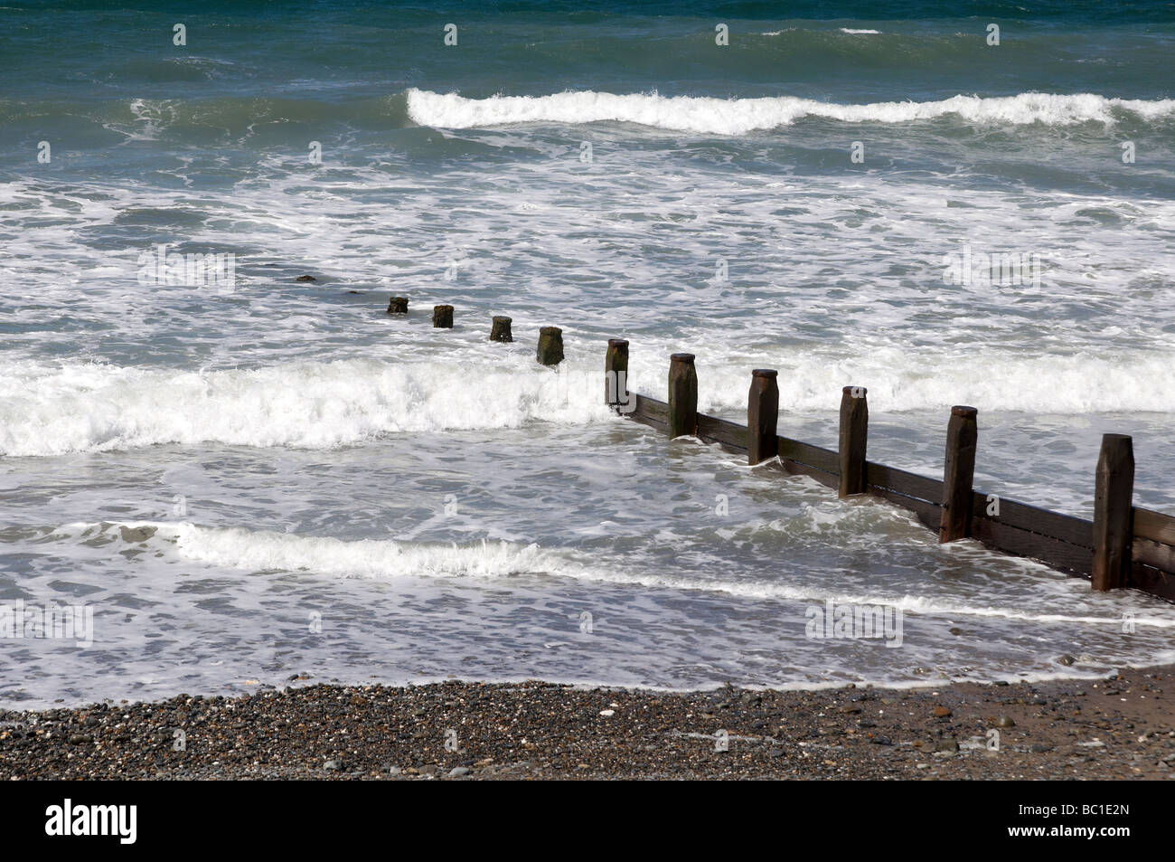 Waves breaking on a beach with a wooden groyne providing basic coastal ...