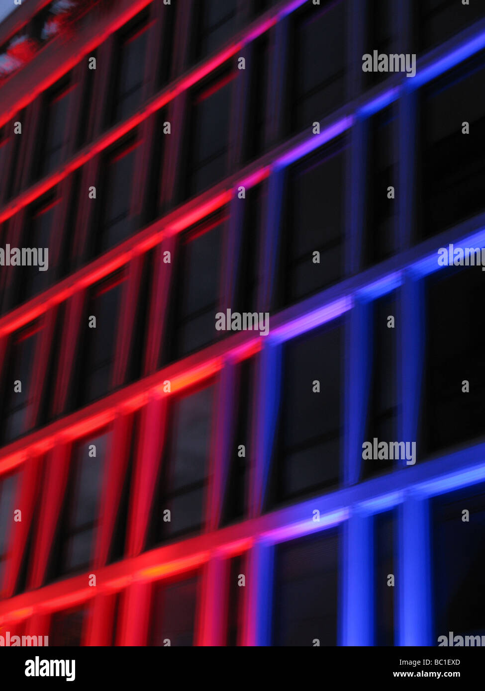 modern office block front illuminated with colourful lights at night ...
