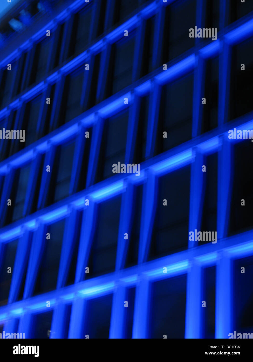 modern office block front illuminated with colourful lights at night ...