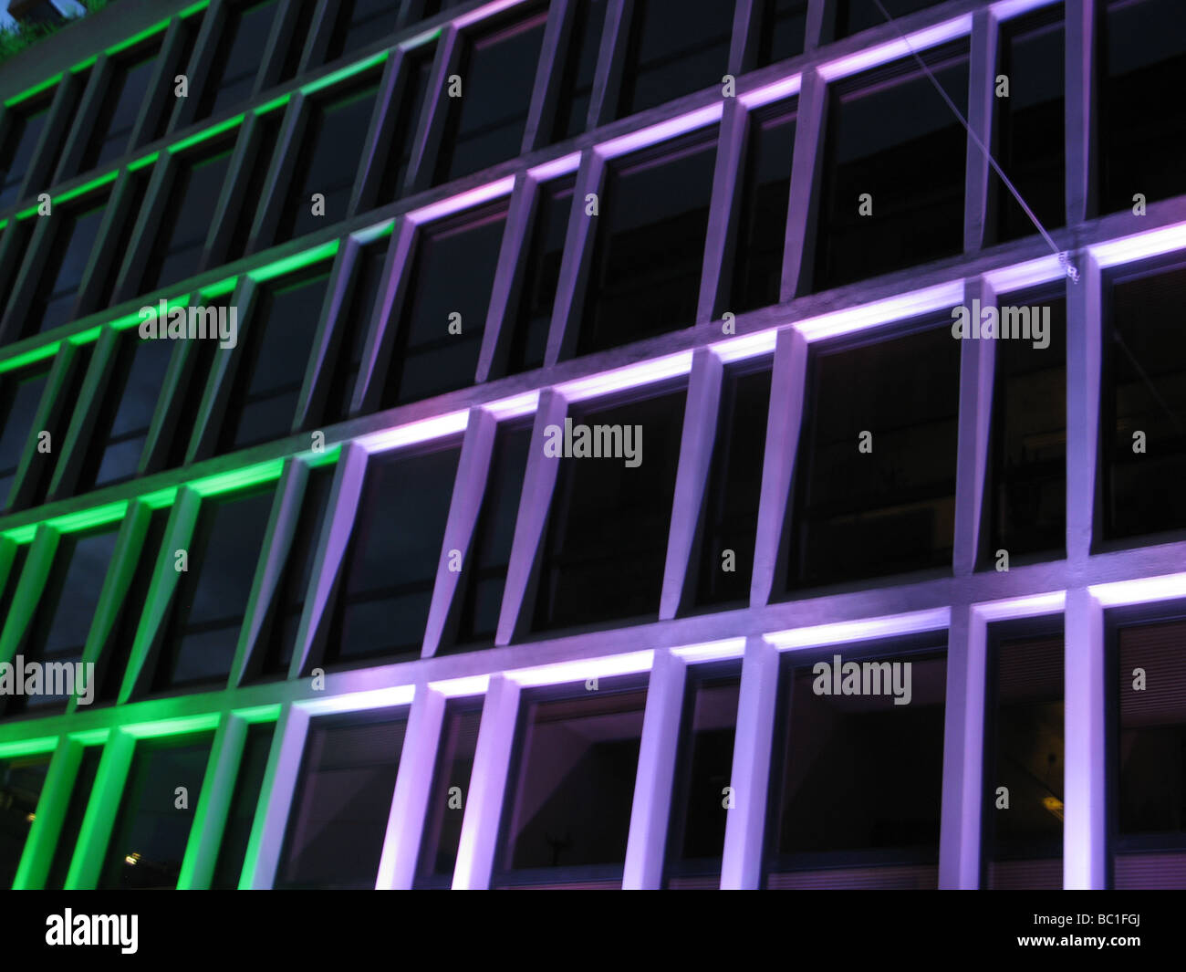 modern office block front illuminated with colourful lights at night ...
