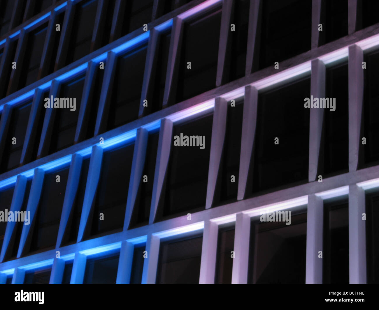 modern office block front illuminated with colourful lights at night ...