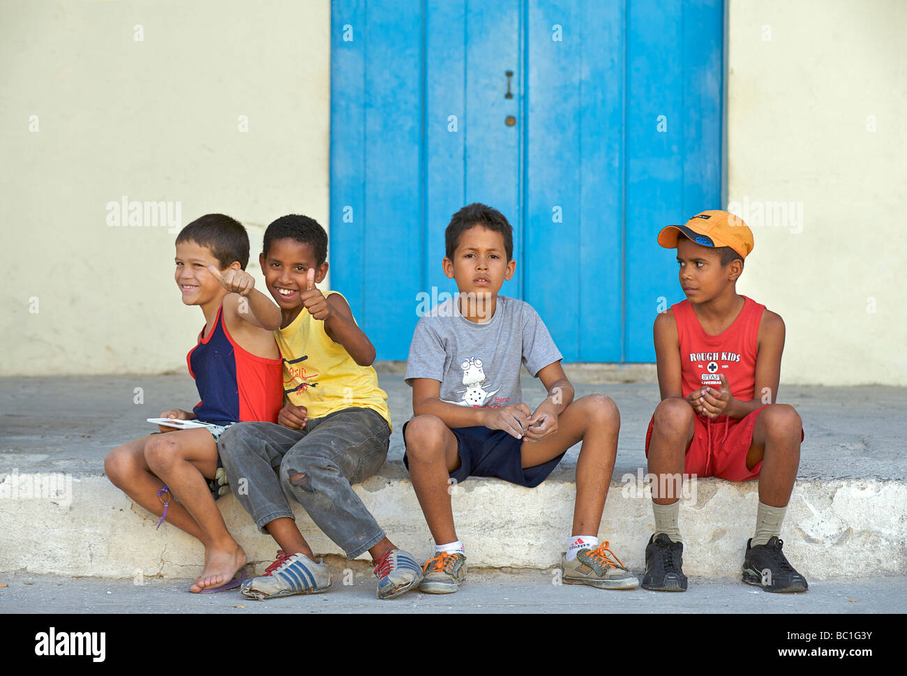 Friends. Four Cuban boys siting on a step, Plaza Vieja, Havana, Cuba ...