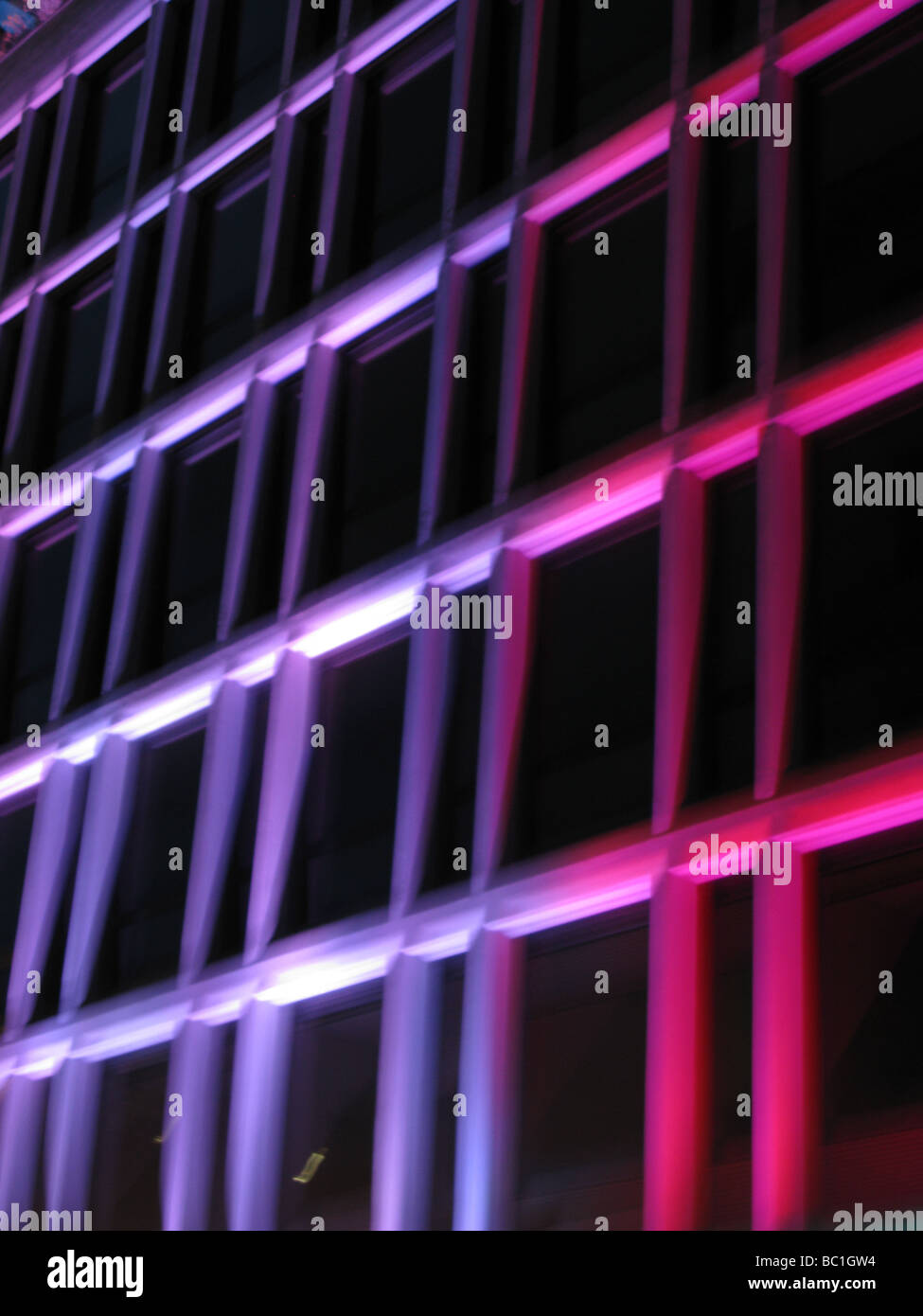 modern office block front illuminated with colourful lights at night ...