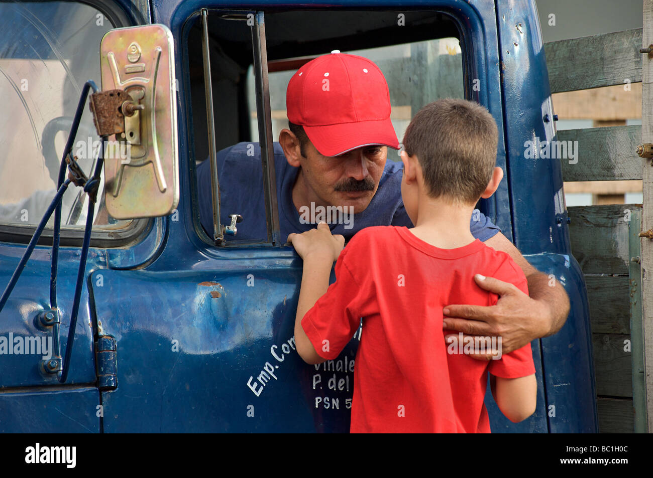 Cuban truck driver embracing his son at the window to his cab. Viñales ...