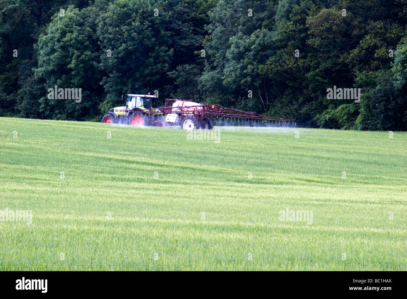 Tractor towing cropsprayer across a field in Kent Stock Photo - Alamy