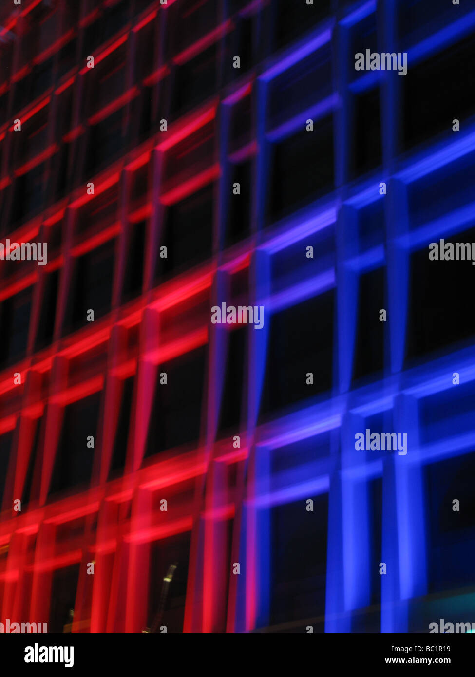modern office block front illuminated with colourful lights at night ...