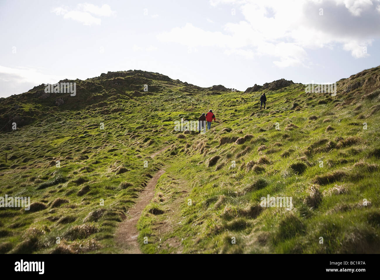 Three adults climbing a hillside Stock Photo - Alamy
