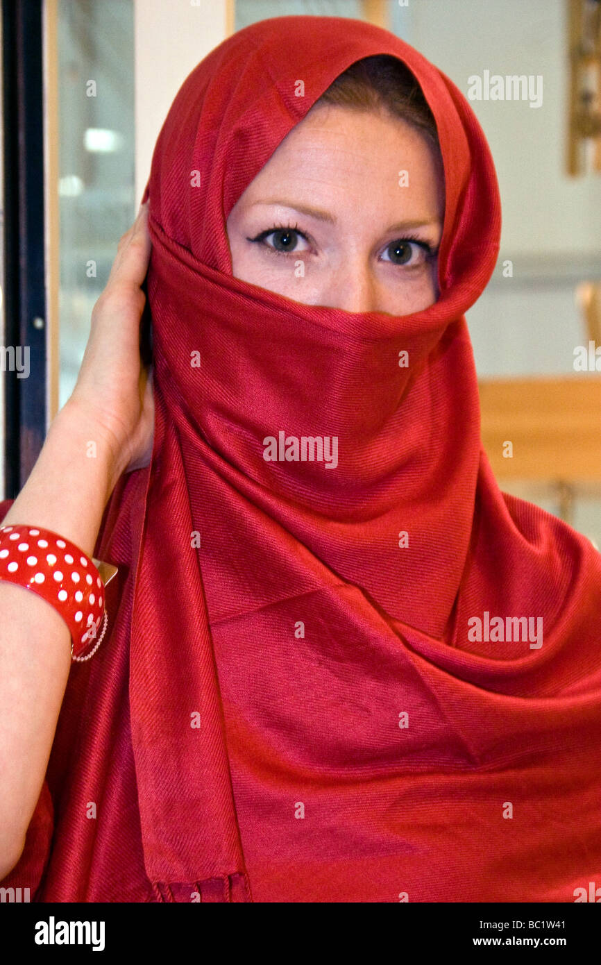 Woman covering her head and face with a red cloth just like a hajib ...