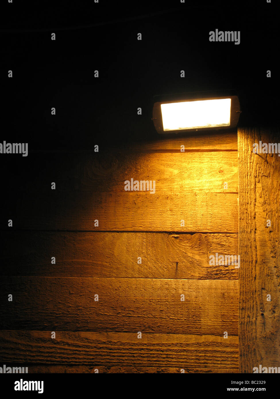 one bright light and high wooden wall at night Stock Photo - Alamy