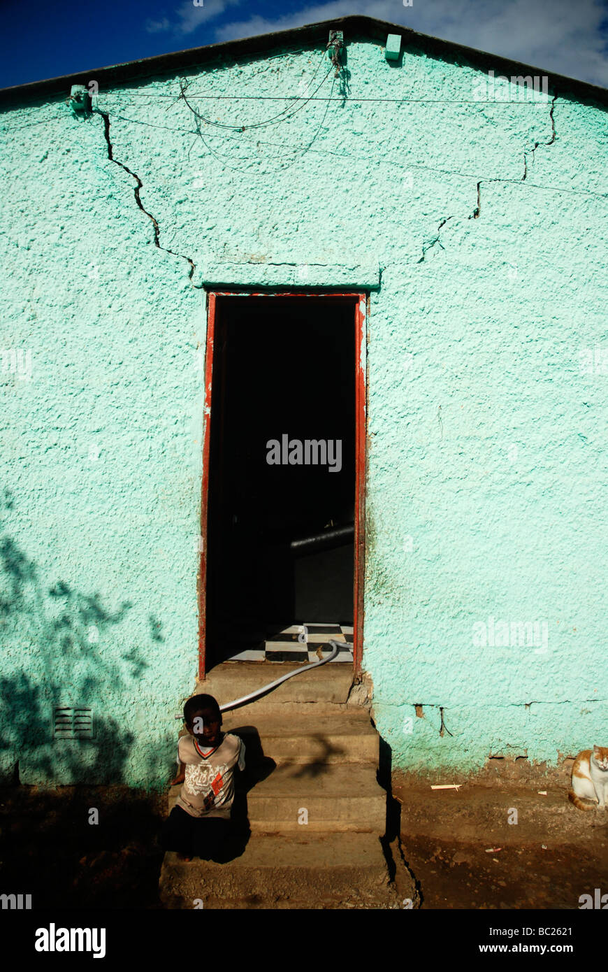 A child plays on the steps in front of his family's disintegrating home ...