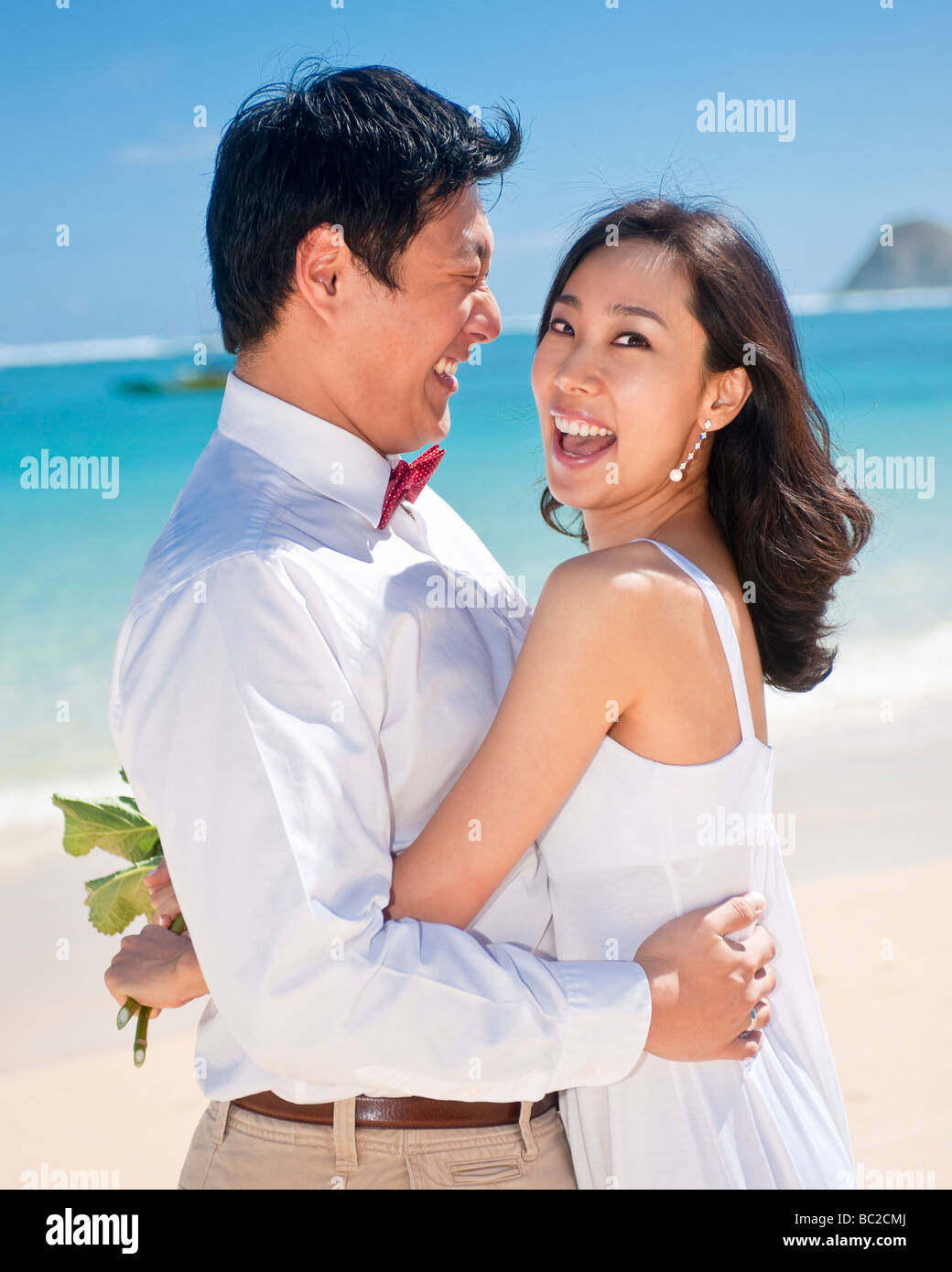 Asian bride and groom joyfully laugh as they celebrate their marriage ...
